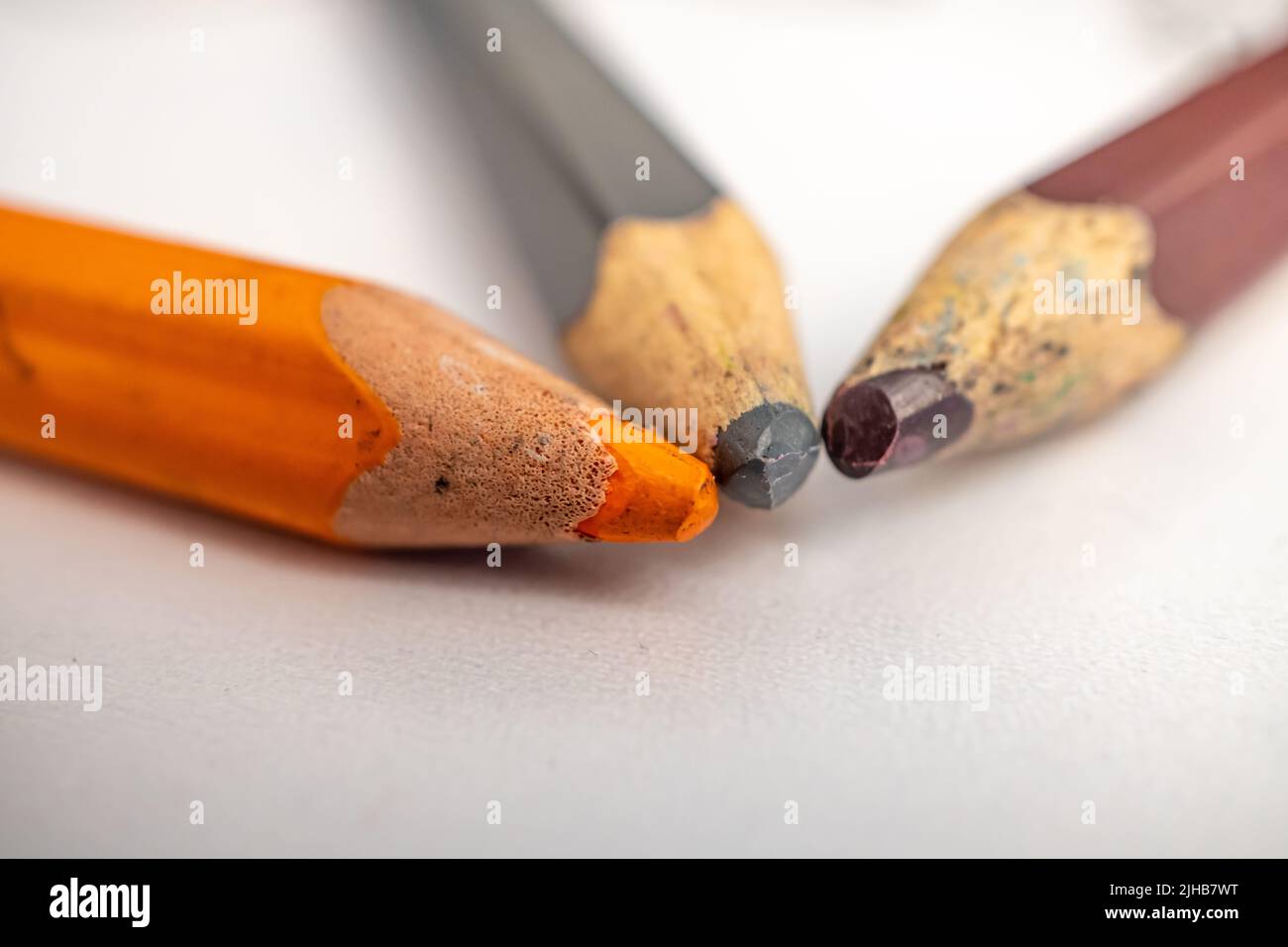 A closeup of orange, black and brown pencils on a white background ...