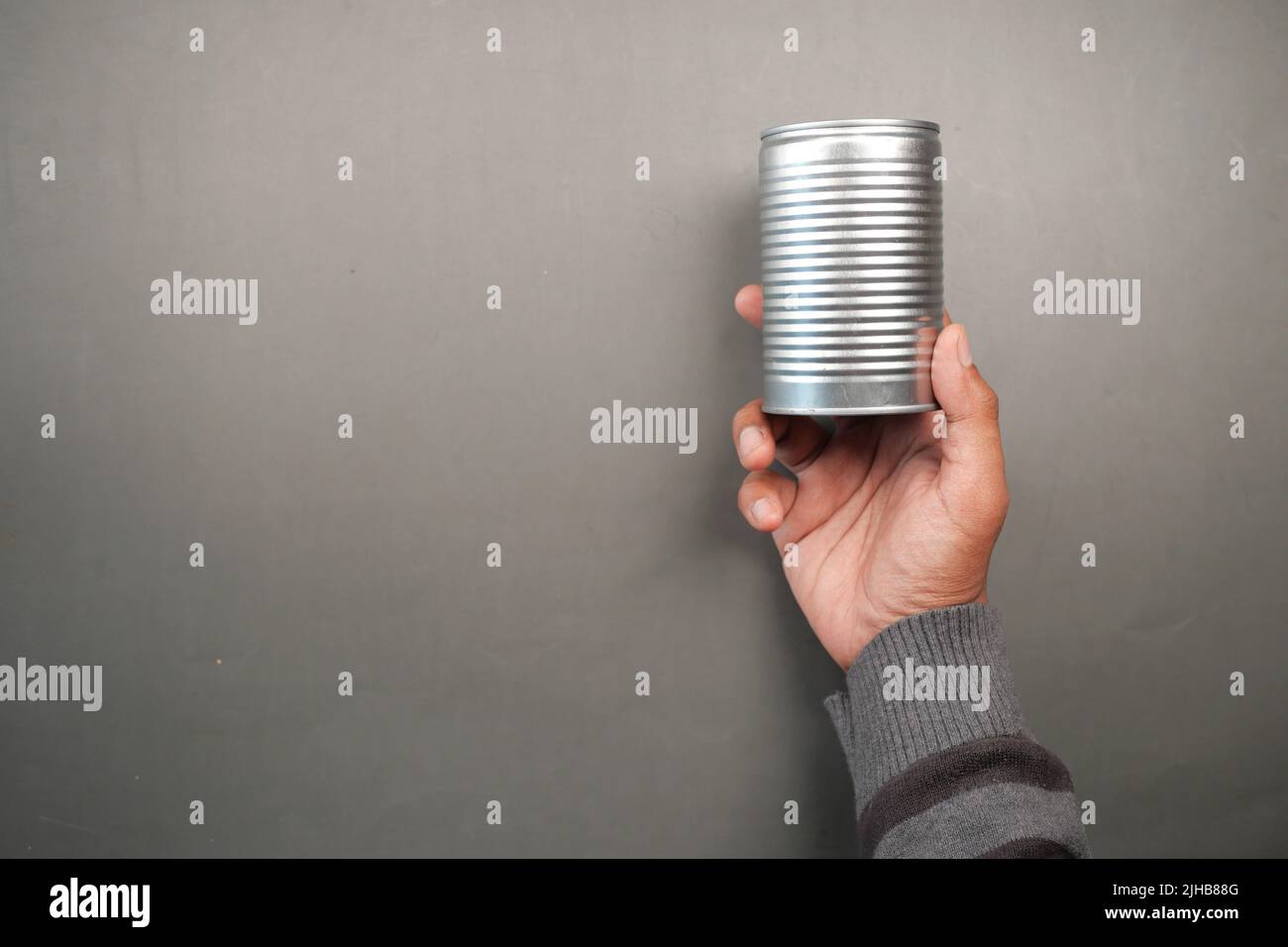 man holding a canned food on black background Stock Photo - Alamy