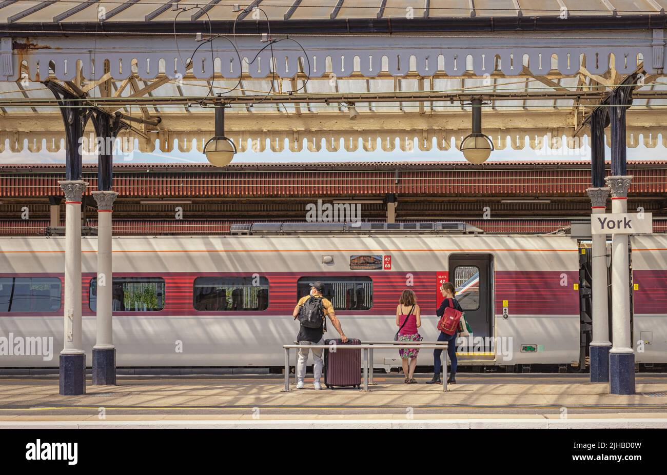 Passengers prepare to enter a train carriage. A historic canopy is ...