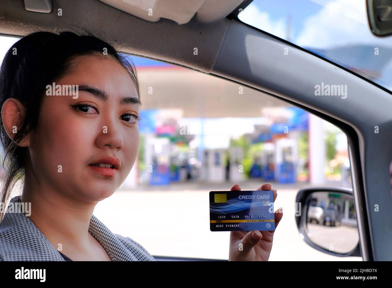 Happy beautiful Asian woman sitting inside her car showing credit card ...