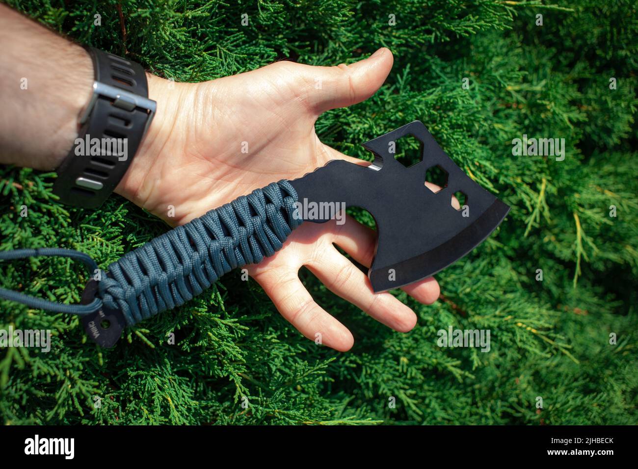 A small black ax with a paracord-wrapped handle. A tool for cutting ...