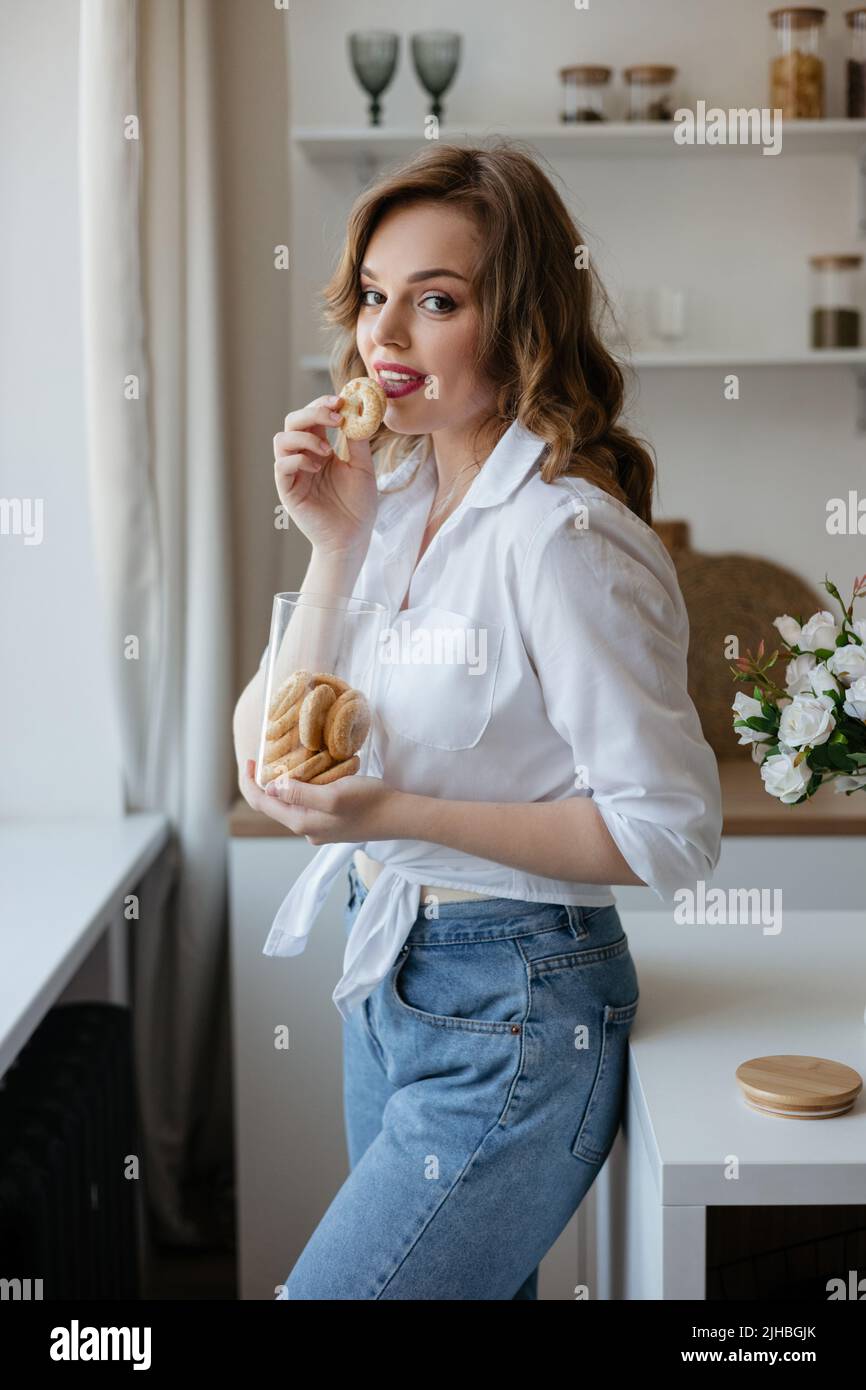 Pretty girl eating cookies in the kitchen Stock Photo - Alamy