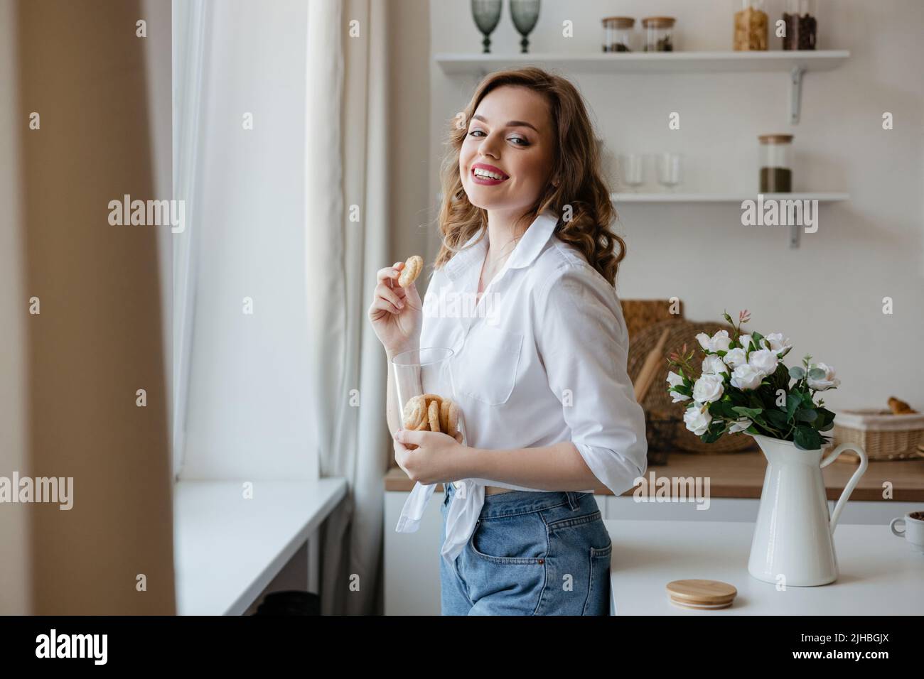 Pretty girl eating cookies in the kitchen Stock Photo - Alamy