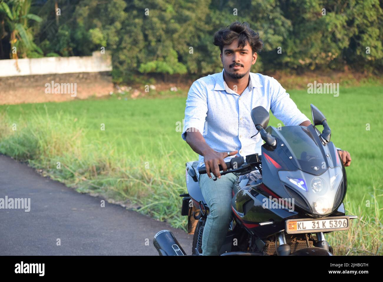 An indian young man riding a motorcycle near a paddy field Stock Photo ...