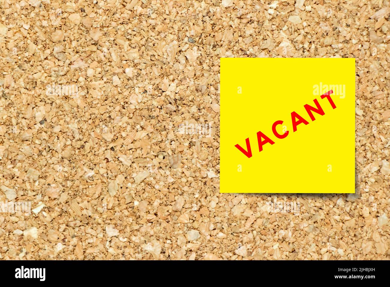 Yellow note paper with word vacant on cork board background with copy ...