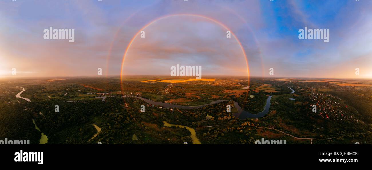 Round rainbow over the river on a summer evening Stock Photo - Alamy
