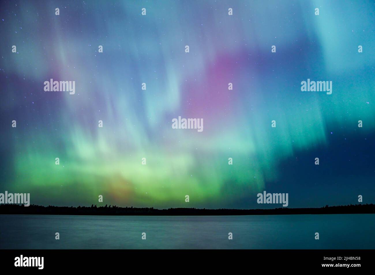 Northern lights erupt over a lake in Minnesota in the dark sky overhead ...