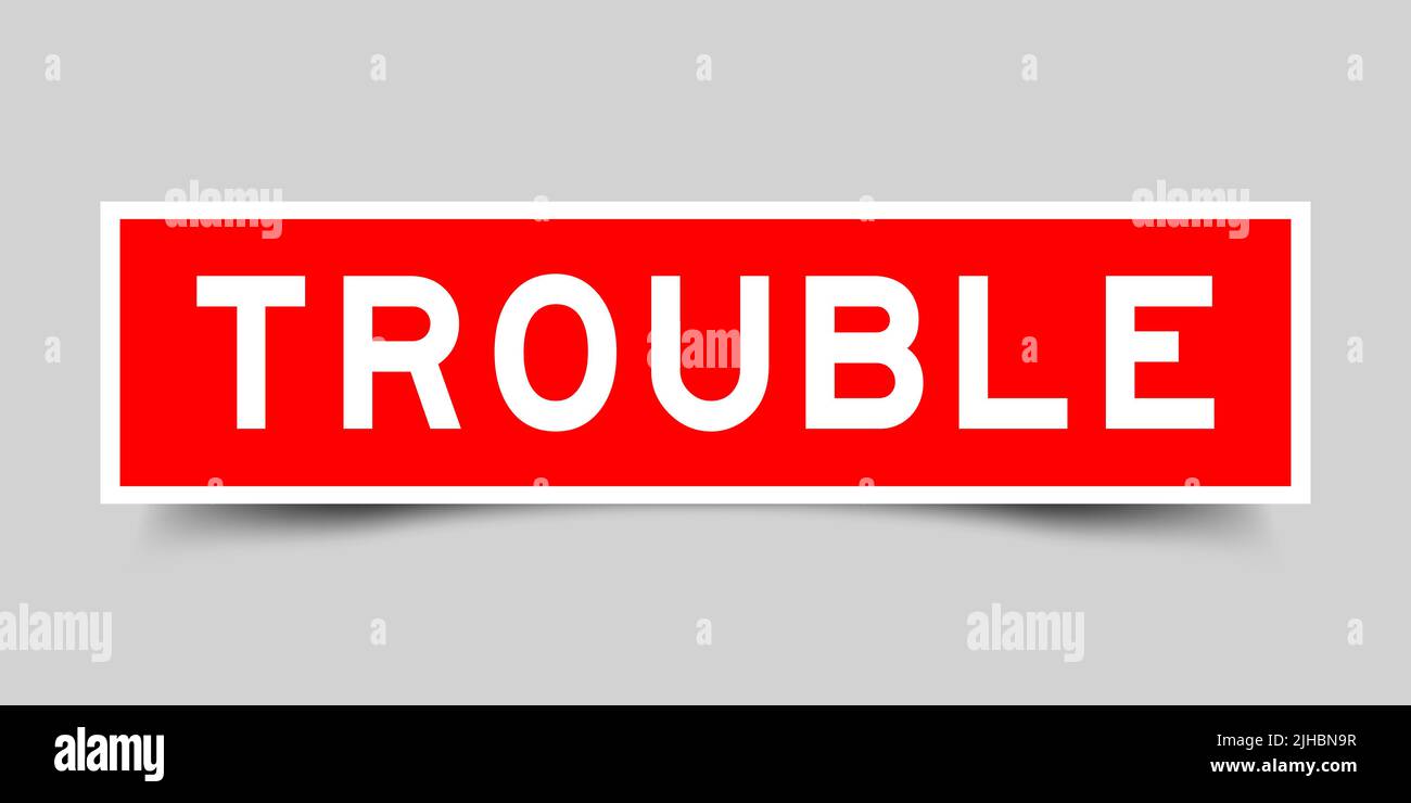 Red color square shape sticker label with word trouble on gray ...
