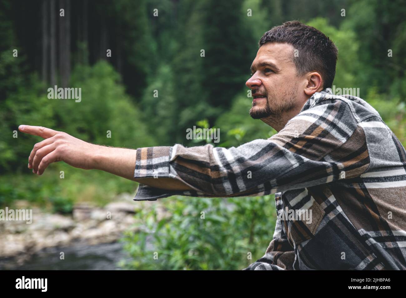 A young man in the forest near the river enjoys nature, a halt Stock ...