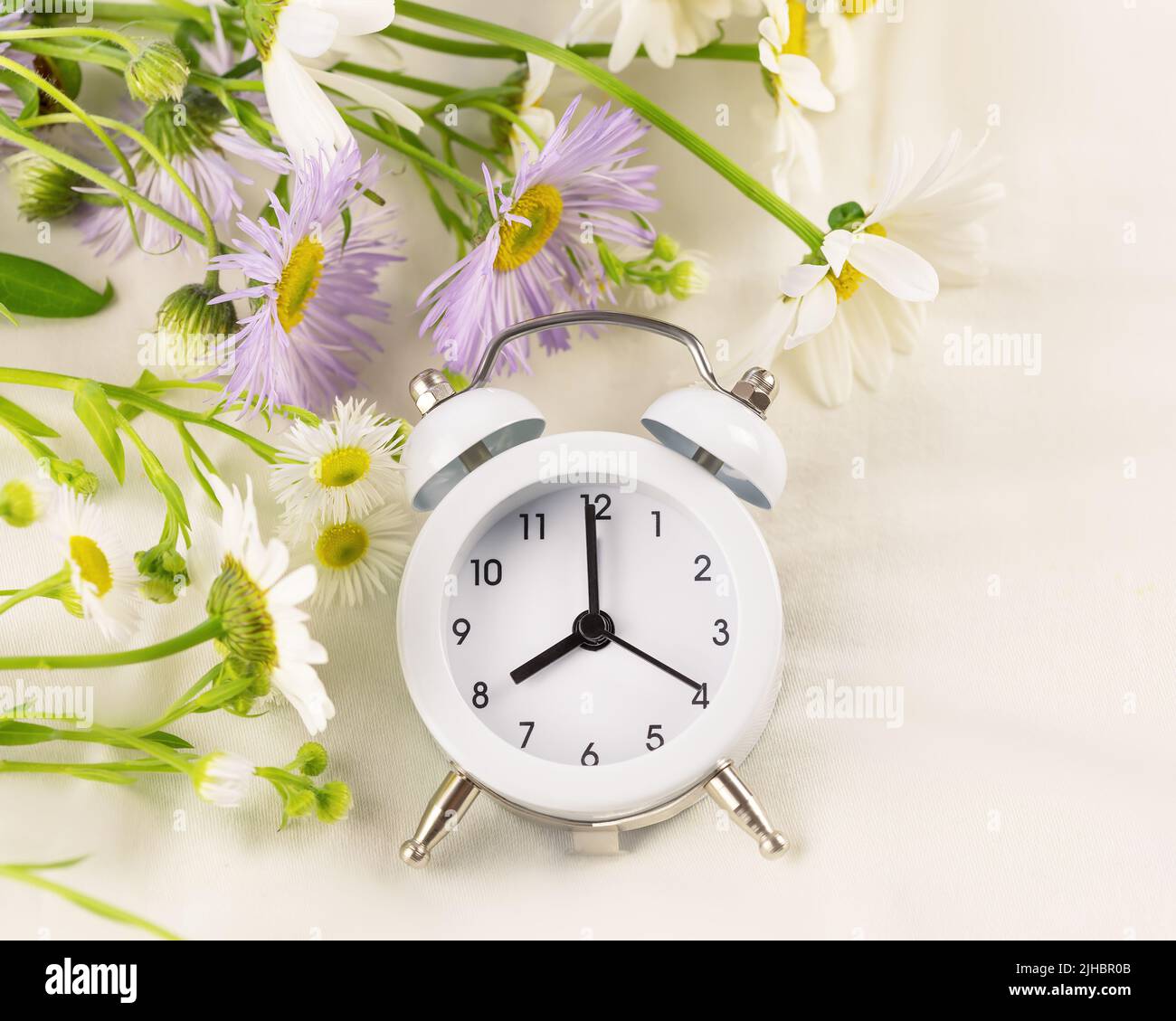Good morning card with wild flowers and alarm clock on a white textile ...