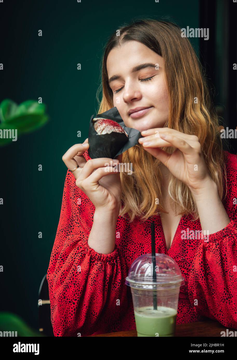 A young woman enjoys a raspberry muffin in a cafe Stock Photo - Alamy