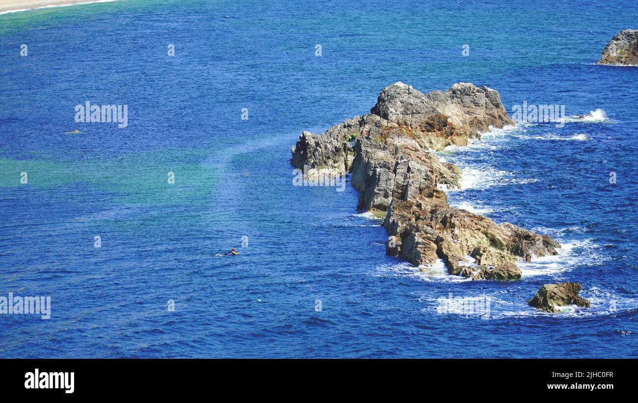 An aerial view of a beautiful blue seascape with rocky cliffs in sunny ...