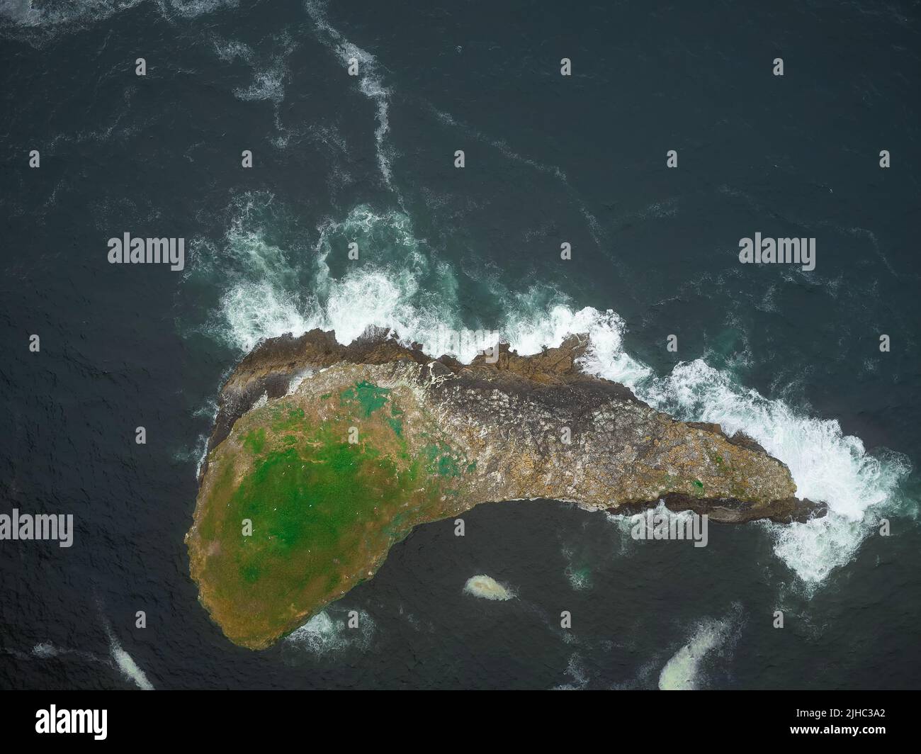 Aerial view. A stone island in the ocean that looks like a big fish. In ...