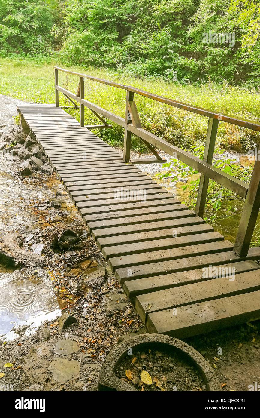 Simple wooden footbridge to cross a stream at a hiking trail in germany ...