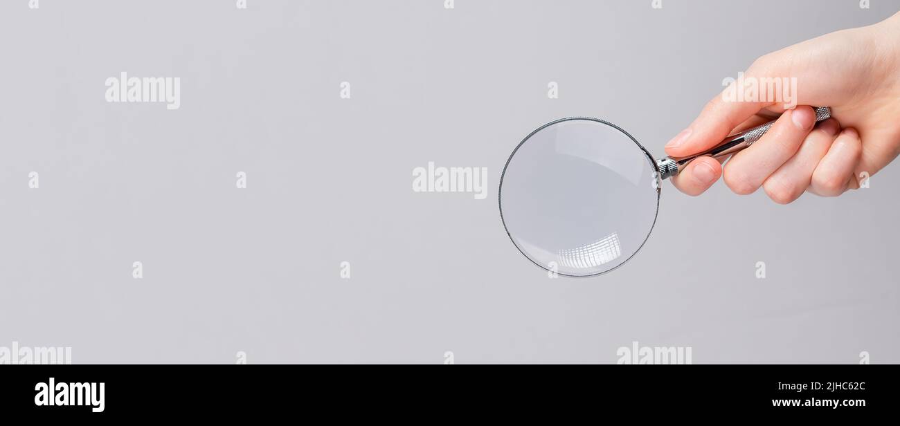 Magnifying lens in hand on gray banner with copy space for text Stock ...