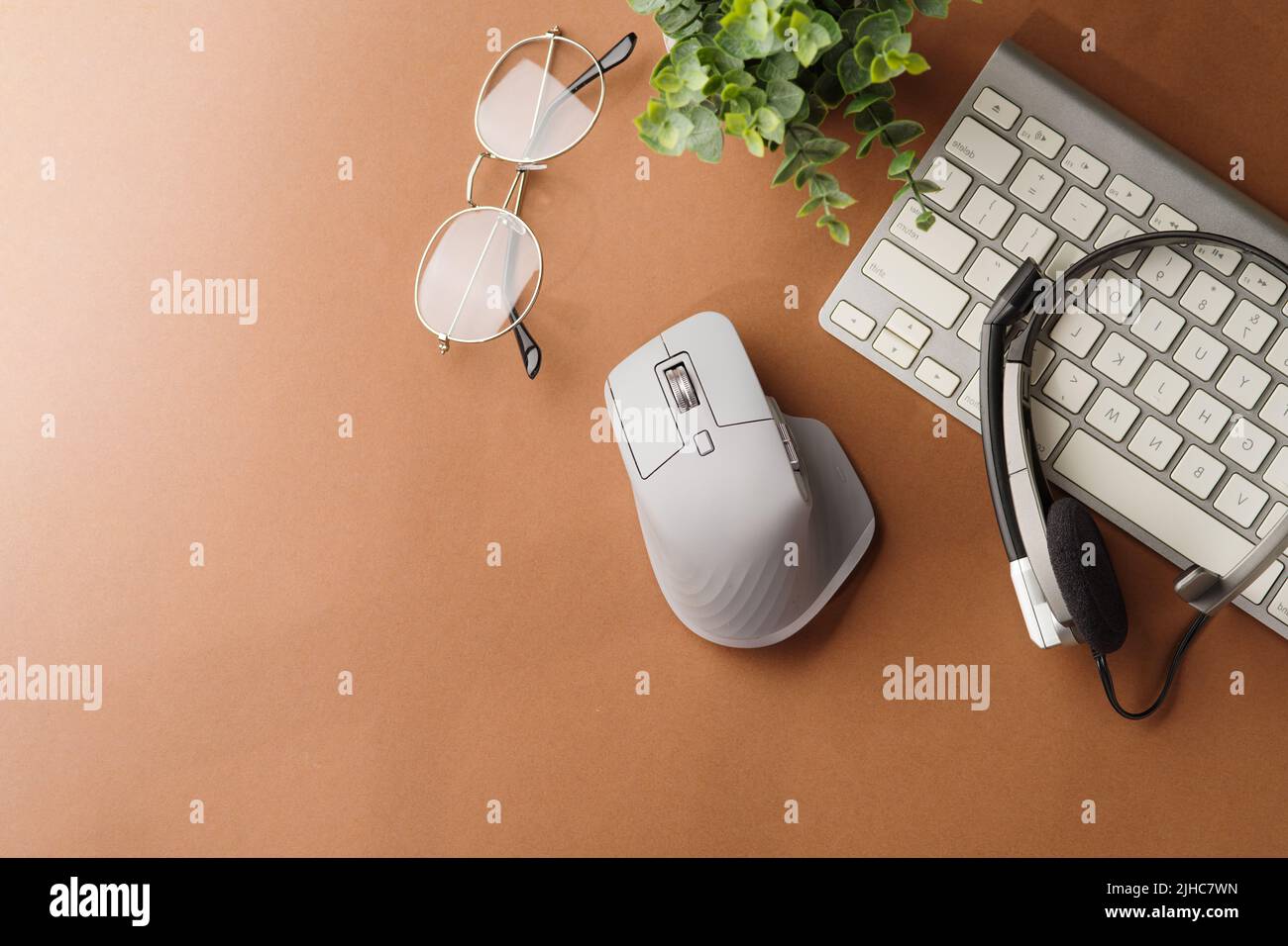 Computer mouse, headphones on a computer keyboard, glasses and indoor ...