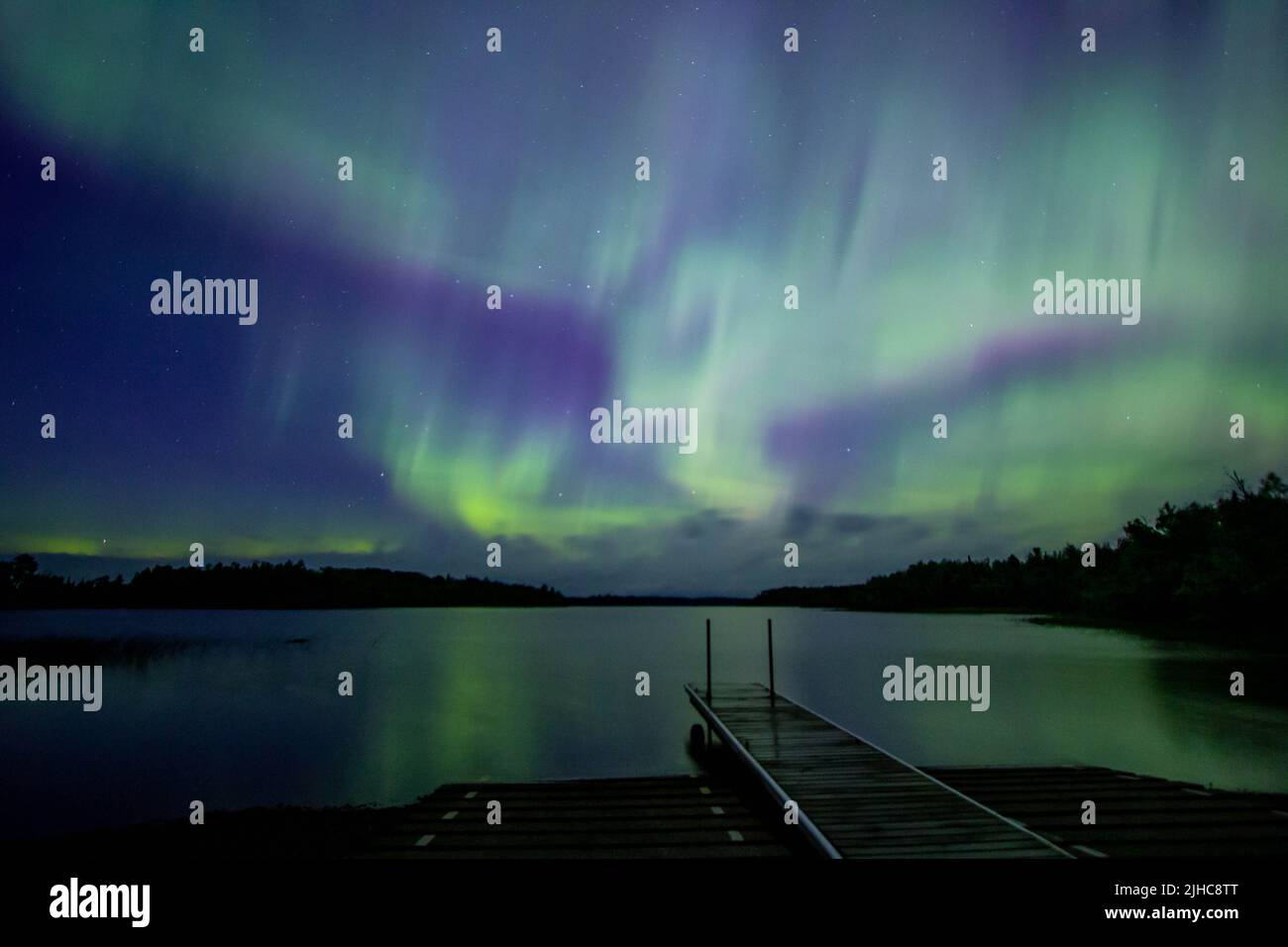 Northern lights erupt over a lake in Minnesota in the dark sky overhead ...