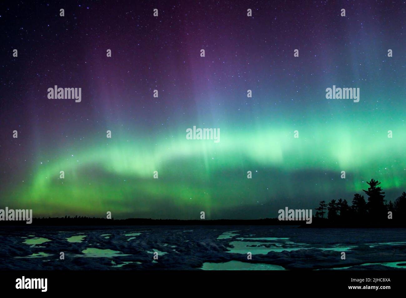Northern lights erupt over a lake in Minnesota in the dark sky overhead ...