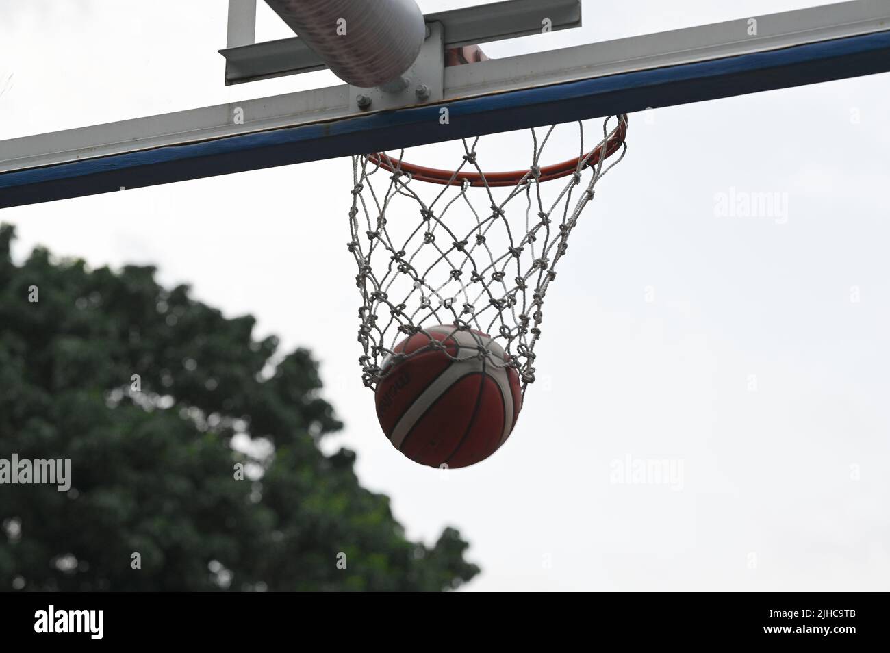 A low angle shot of a red basketball falling out of the bottom of a ...