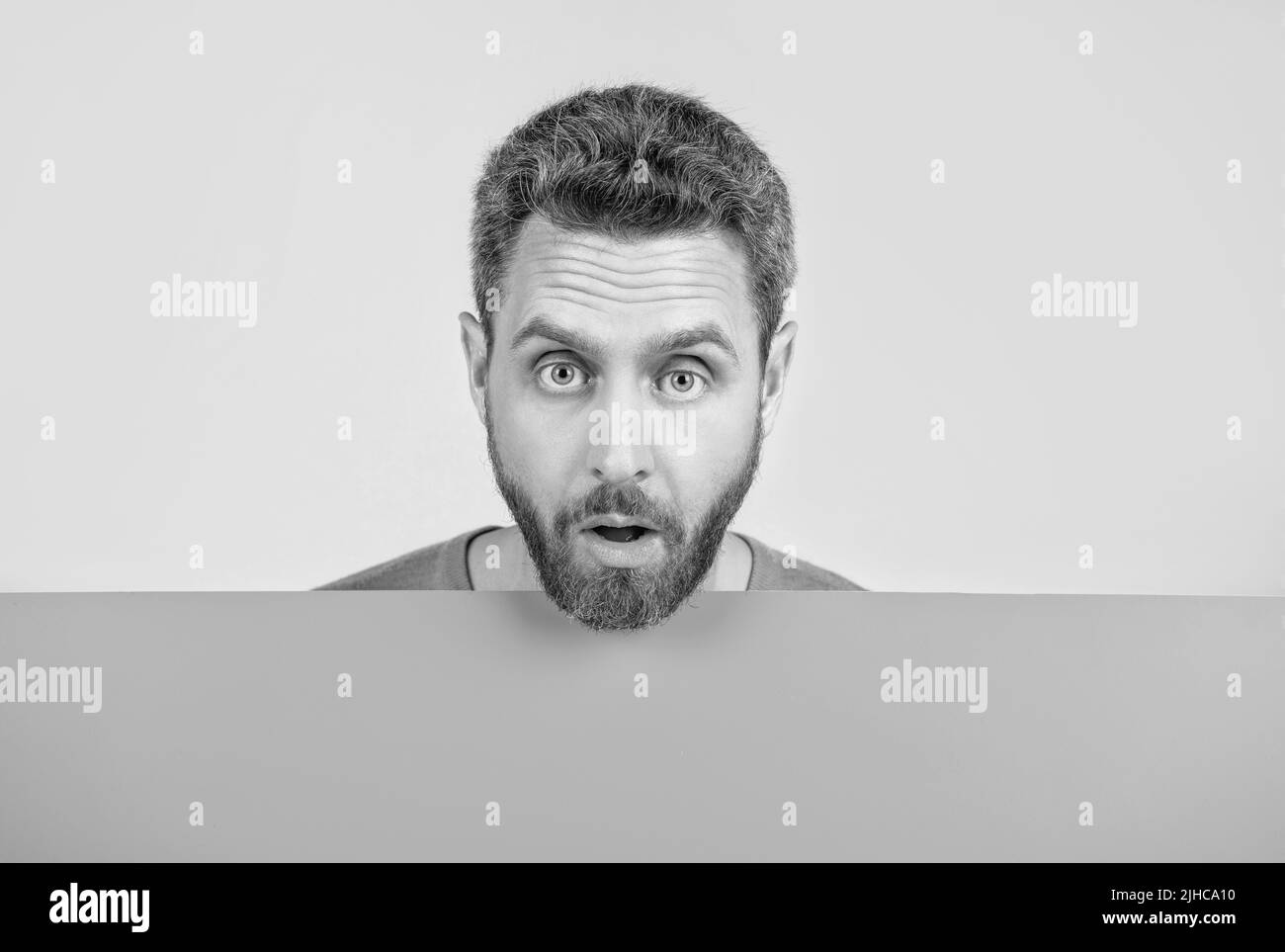 surprised mature bearded man behind orange black paper banner with copy ...
