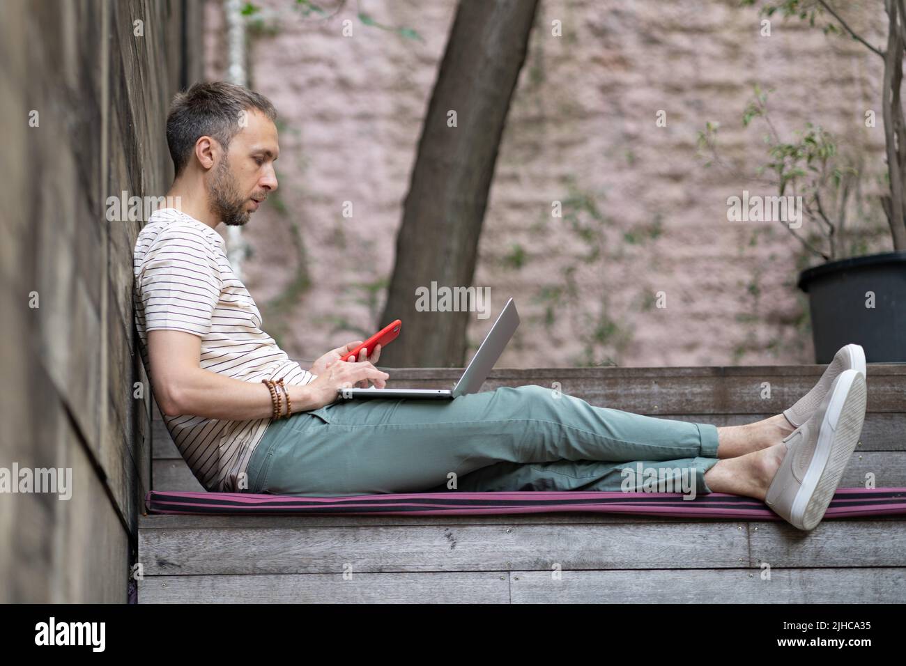 Focused young man entrepreneur sitting outside with laptop and ...