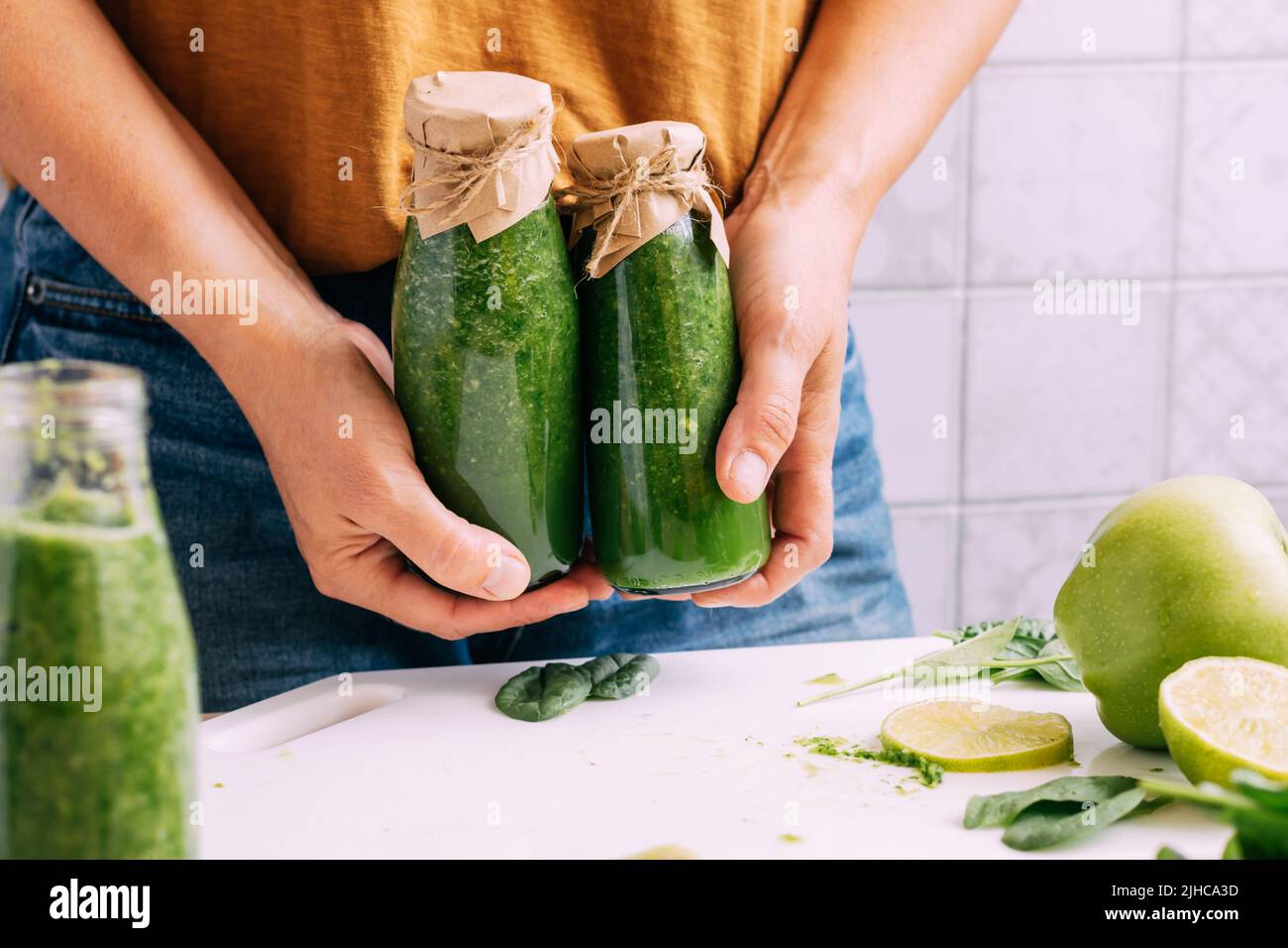 Women's hands hold bottles of freshly prepared smoothies from green ...