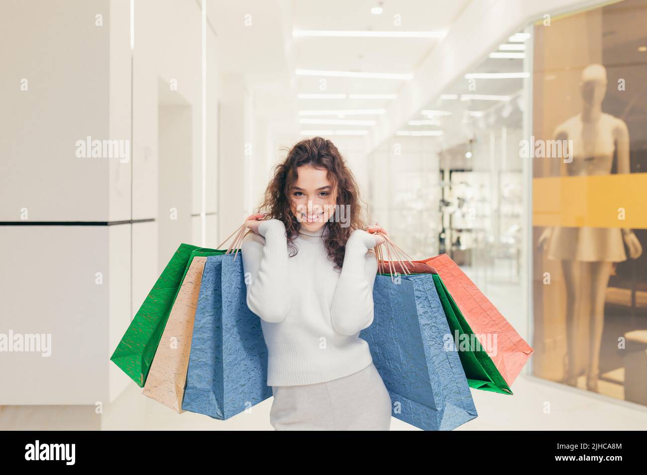 Portrait of a young curly beautiful woman who goes shopping in the mall ...