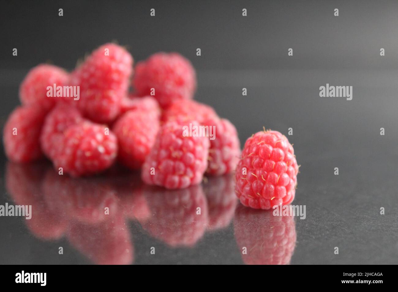 raspberries lie in a stack of piles on a black background close-up. Day ...