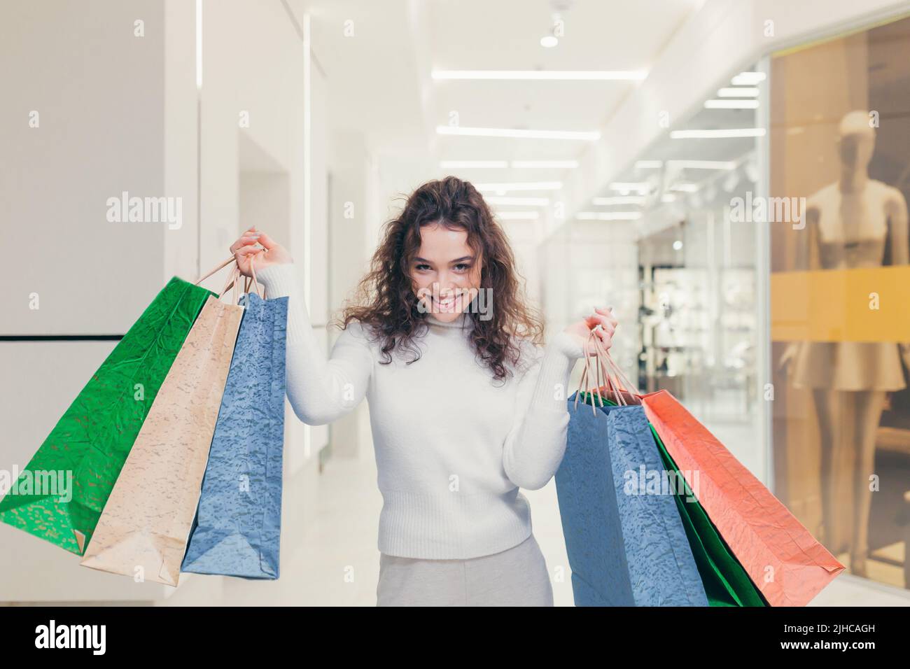 Happy and satisfied young woman, girl shopping in shopping mall. Shows ...