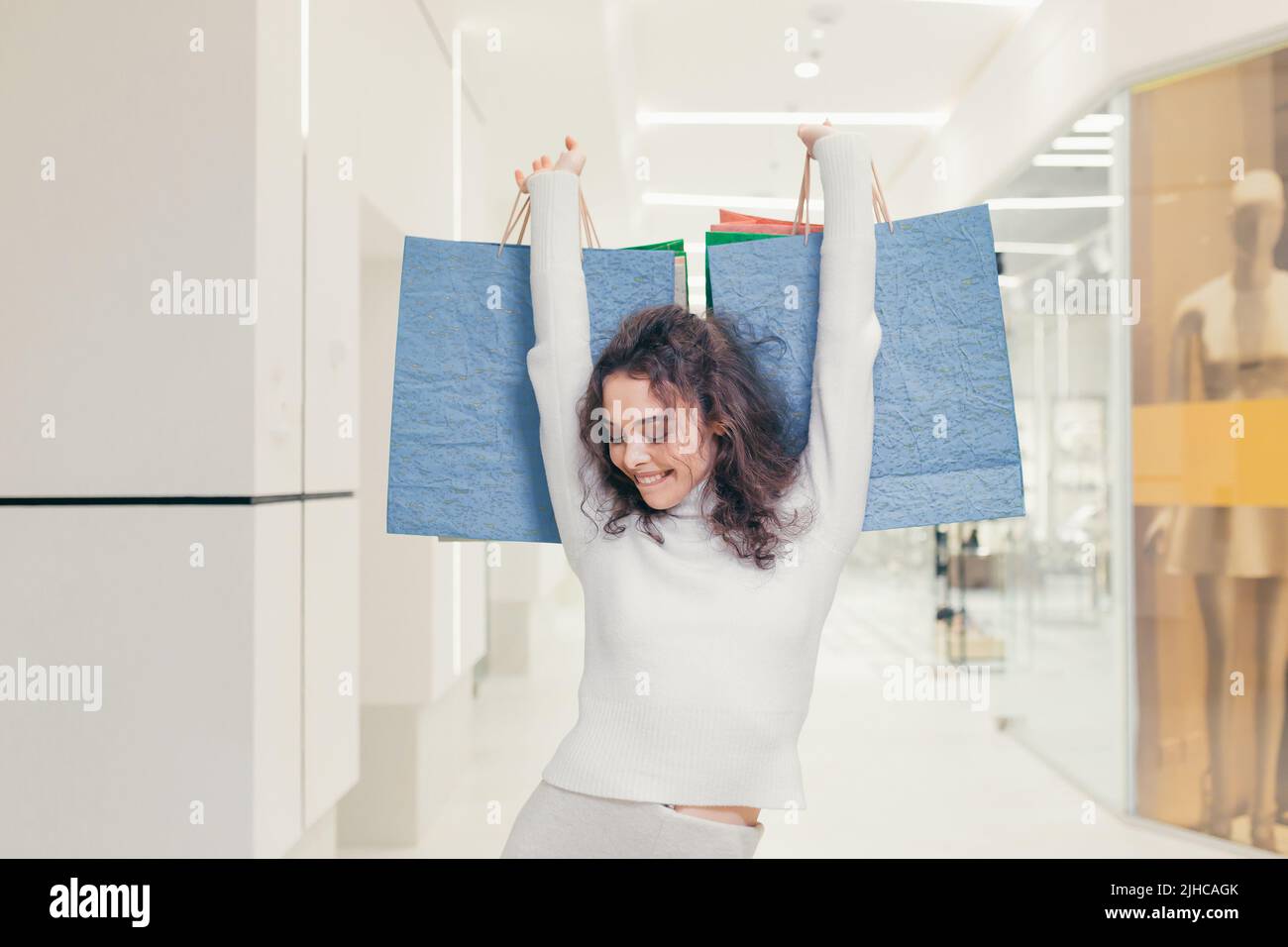 Happy and satisfied young woman, girl shopping in shopping mall. Shows ...