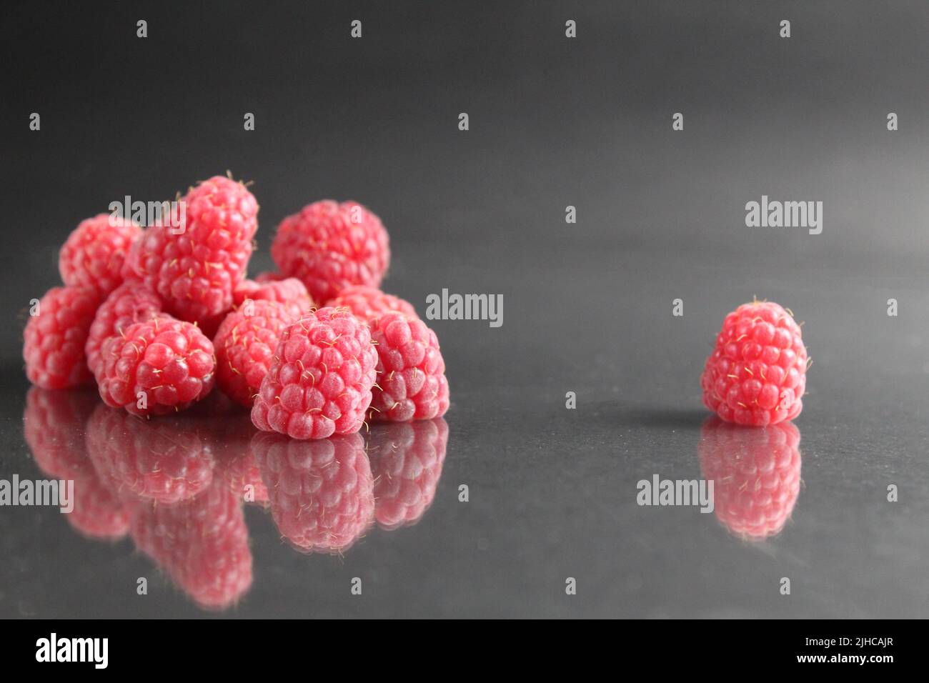 raspberries lie in a stack of piles on a black background close-up. Day ...