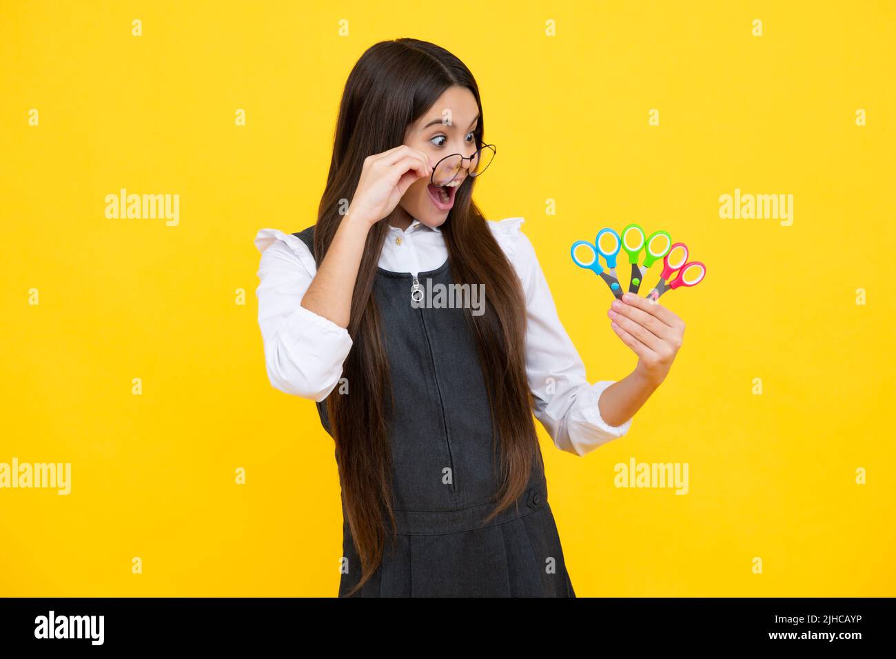 Teenage school girl with scissors, isolated on yellow background. Child ...
