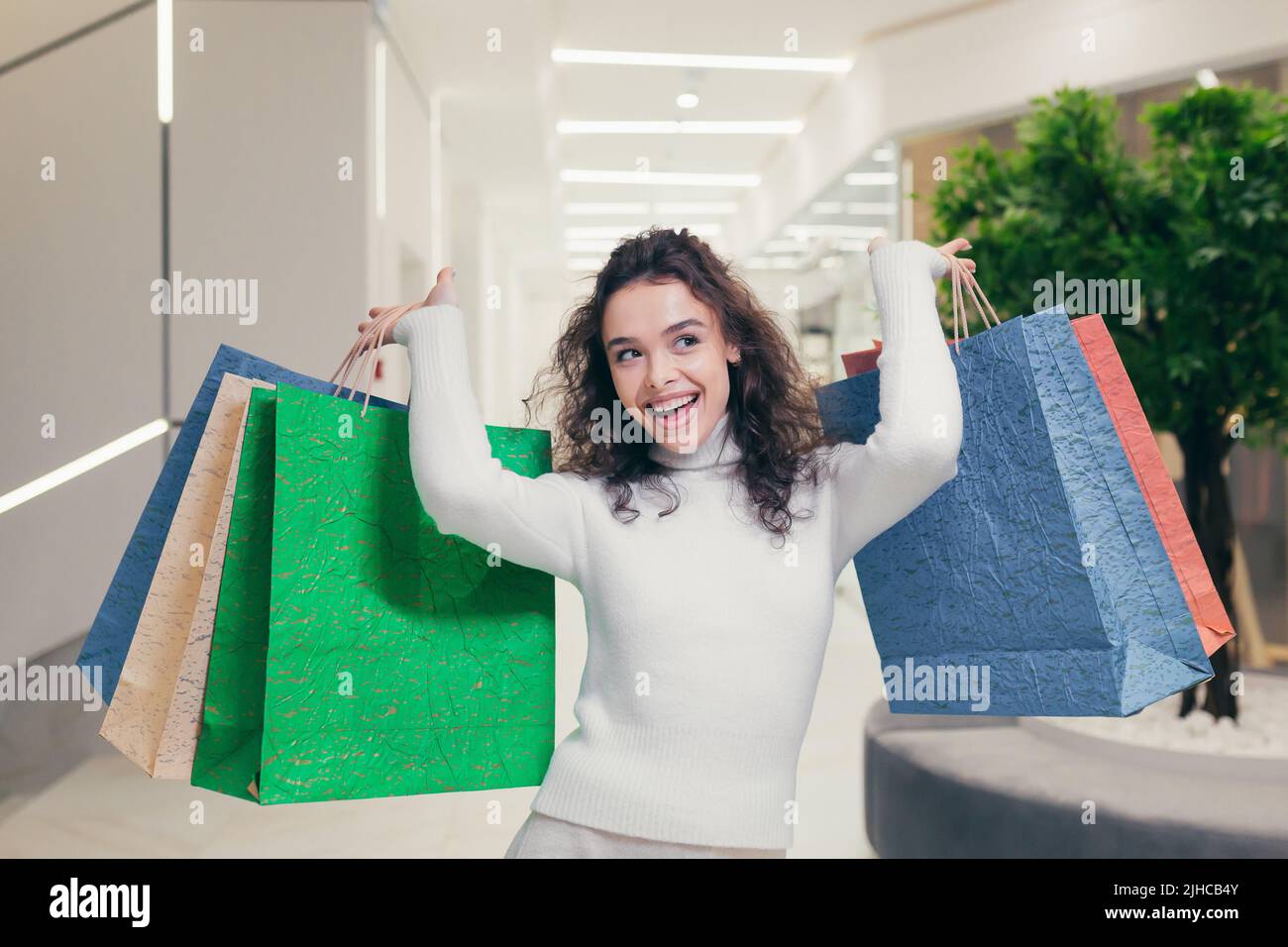 Happy and satisfied young woman, girl shopping in shopping mall. Shows ...