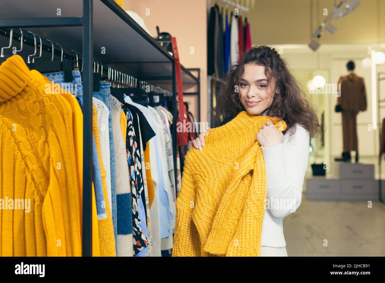 A young beautiful woman with curly hair chooses, looking for a warm ...