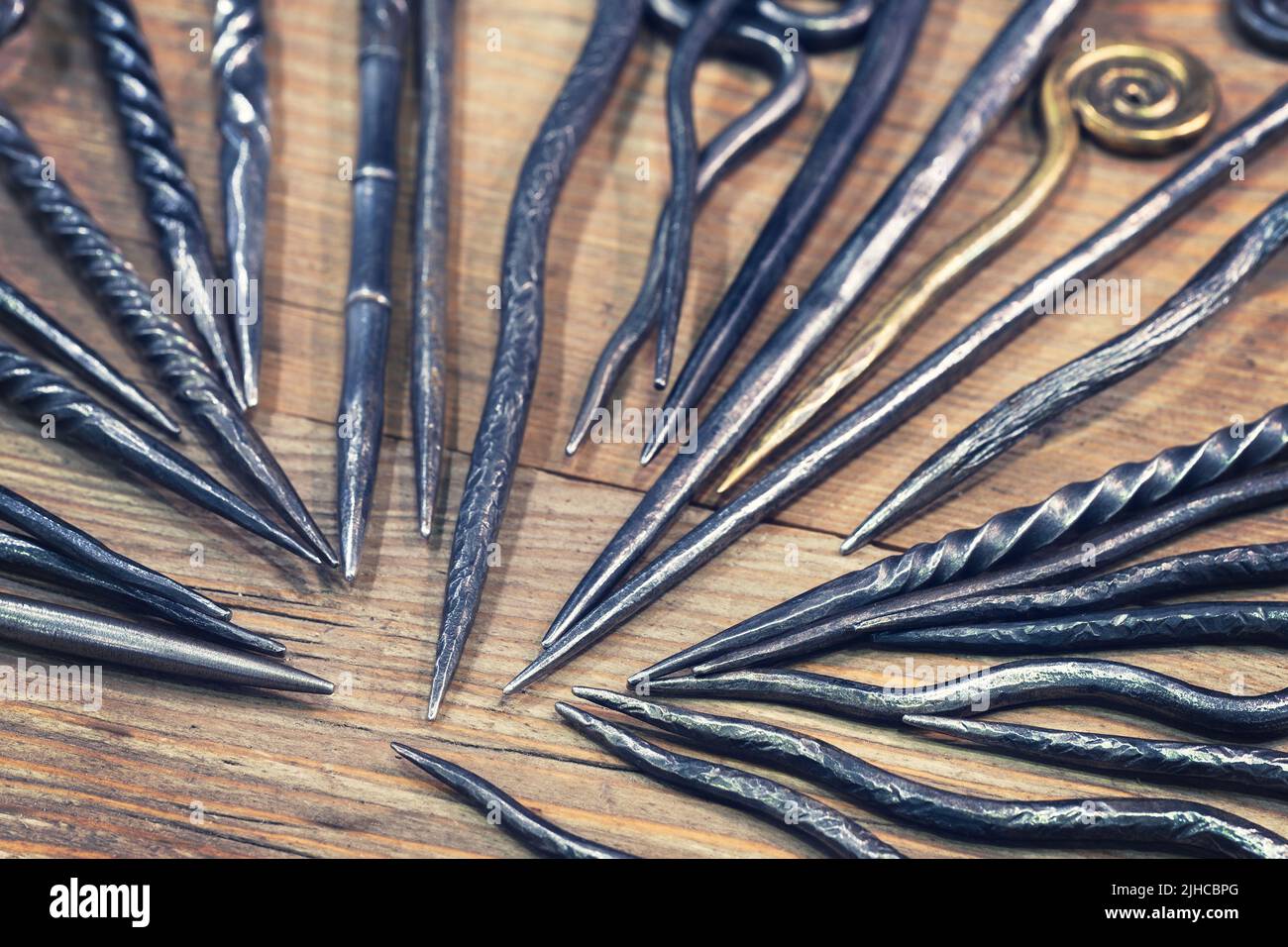 Metal forged products on a wooden background, a pike and an awl are ...