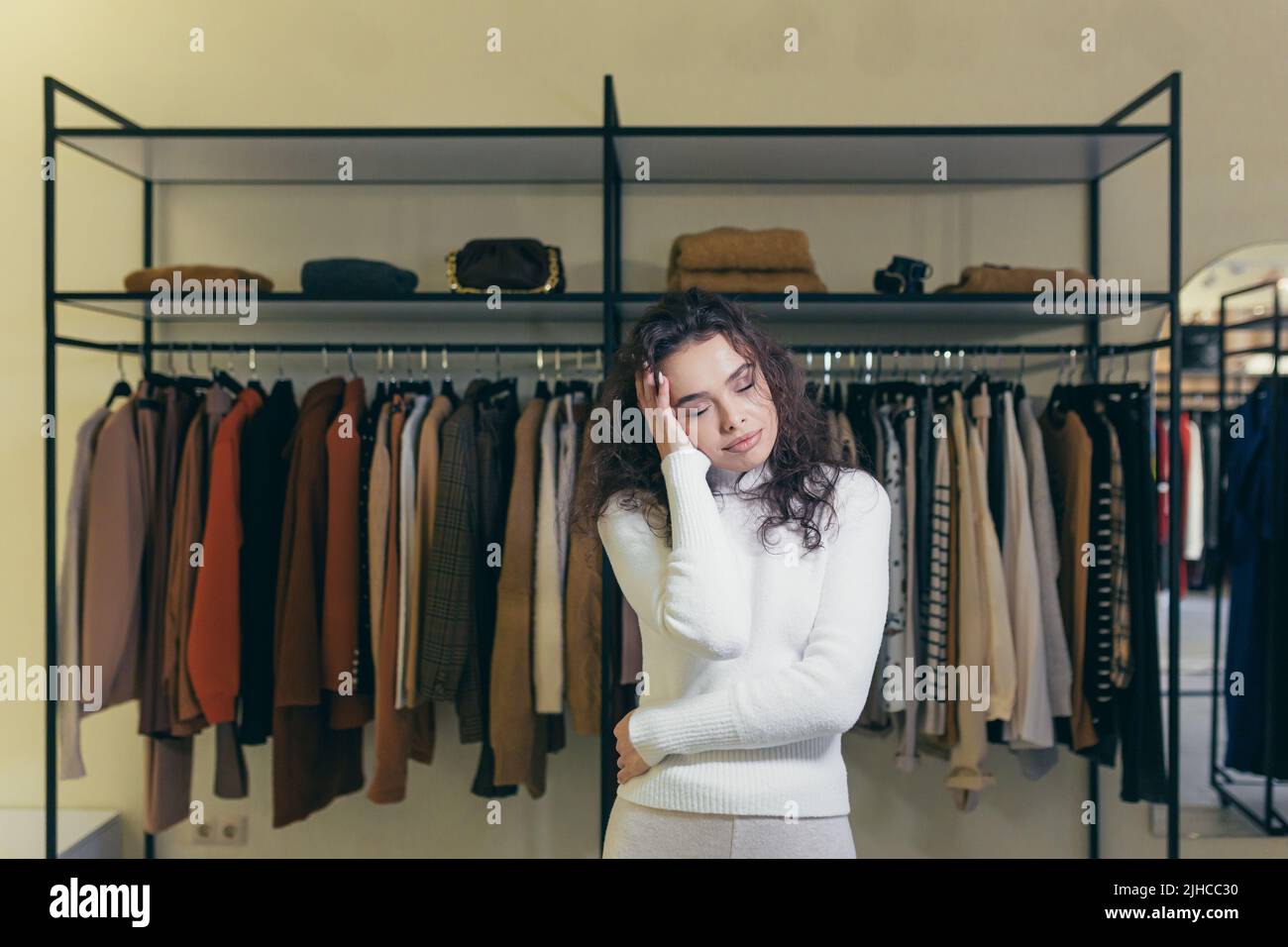 Worried and confused young woman in the store holding her head ...