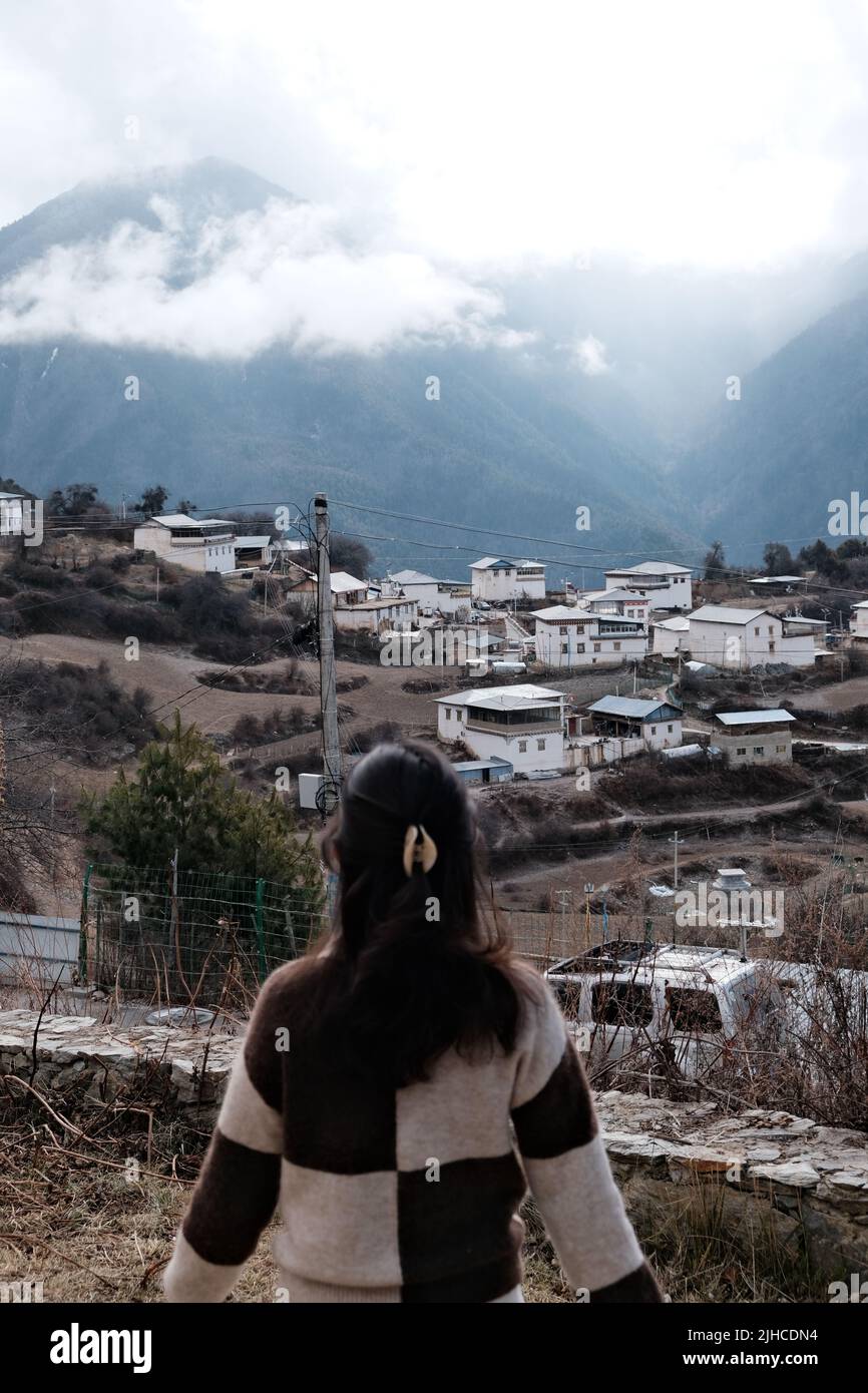 A back view of a female looking at a village with small houses Stock ...