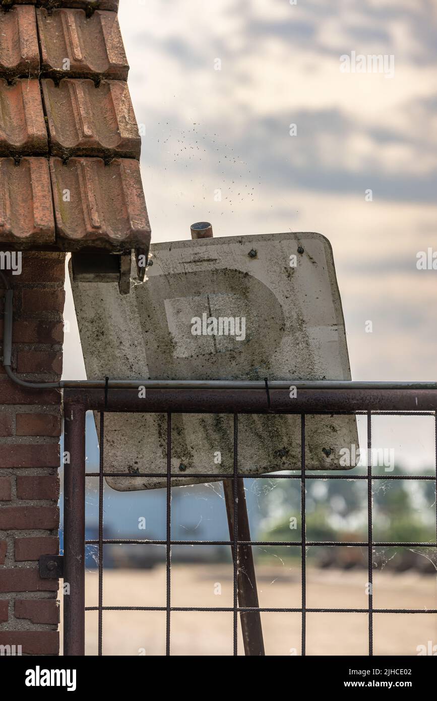 A view of a rusty parking sign leaning on a building behind fence Stock ...