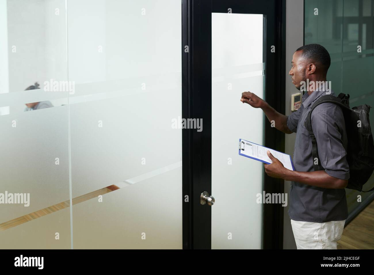 Serious software developer with CV in hands knocking at door of compnay ...