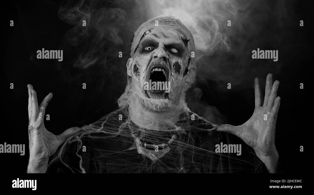 Zombie man with makeup with fake wounds scars and white contact lenses ...