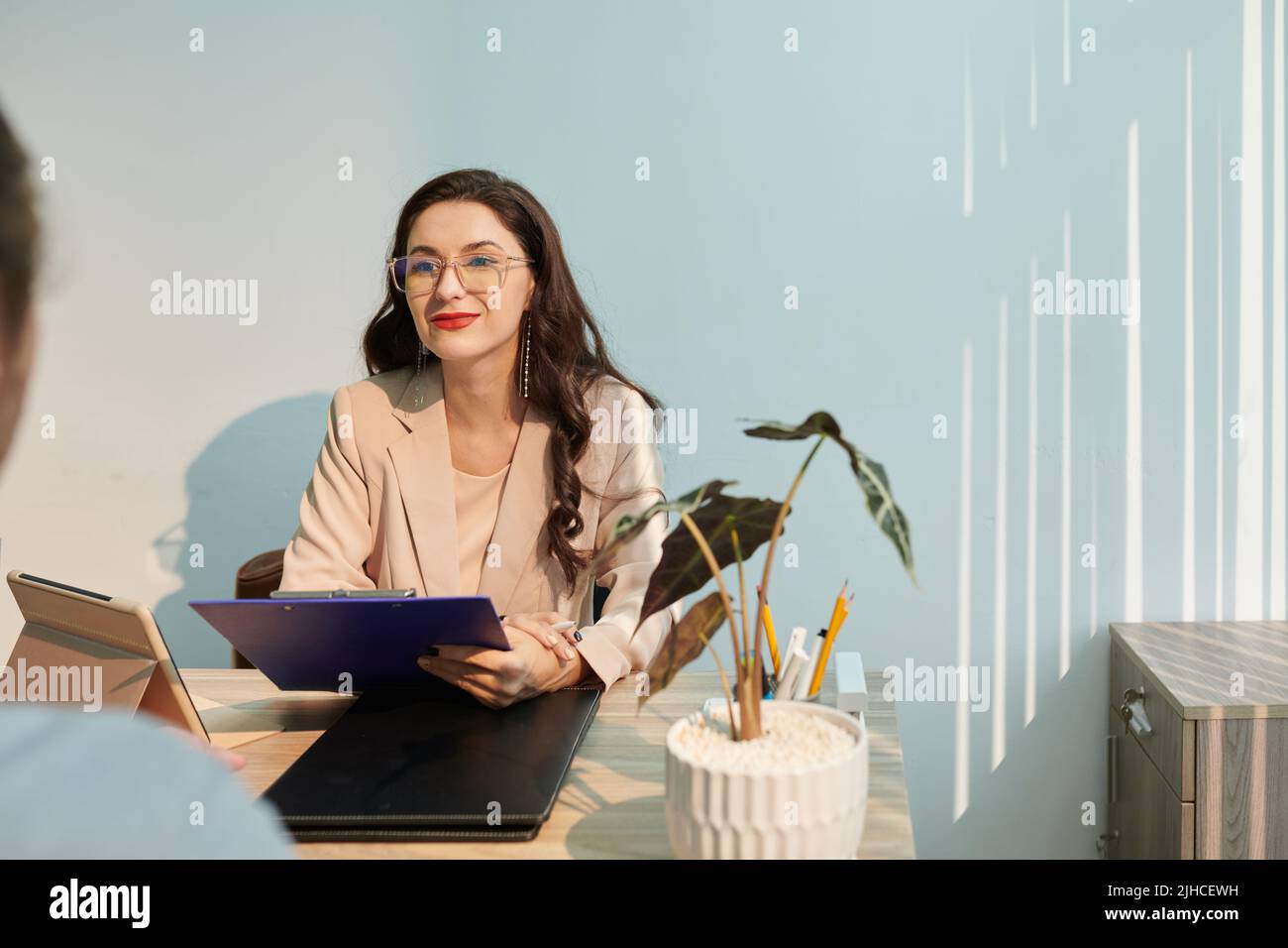 Smiling elegant recruiter talking to job applicant, asking about his ...