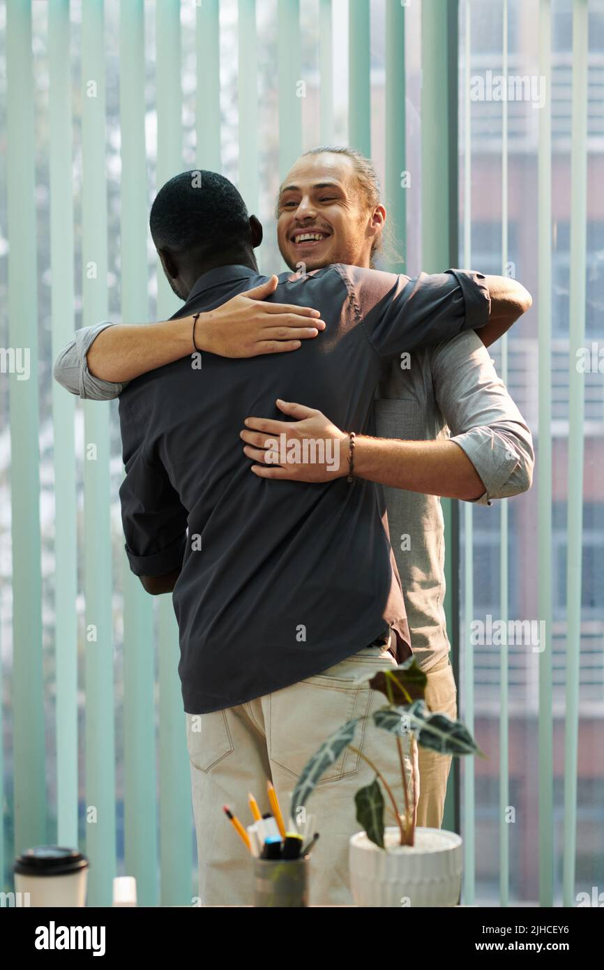 Happy excited employee hugging his collegue returned to work from long ...