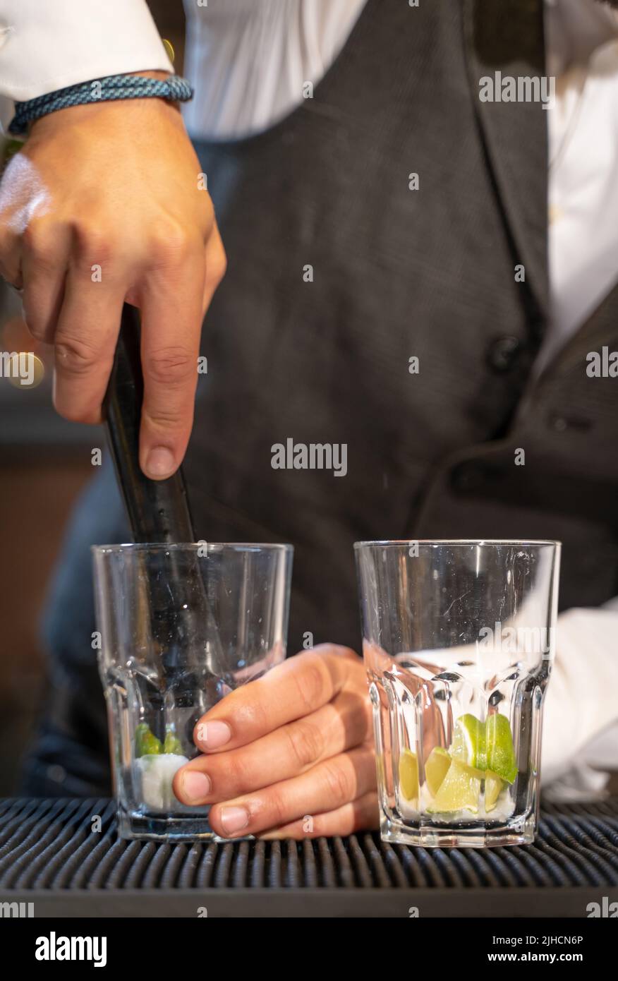 Elegant barman making cocktail Mojito in night club adding ingredients ...