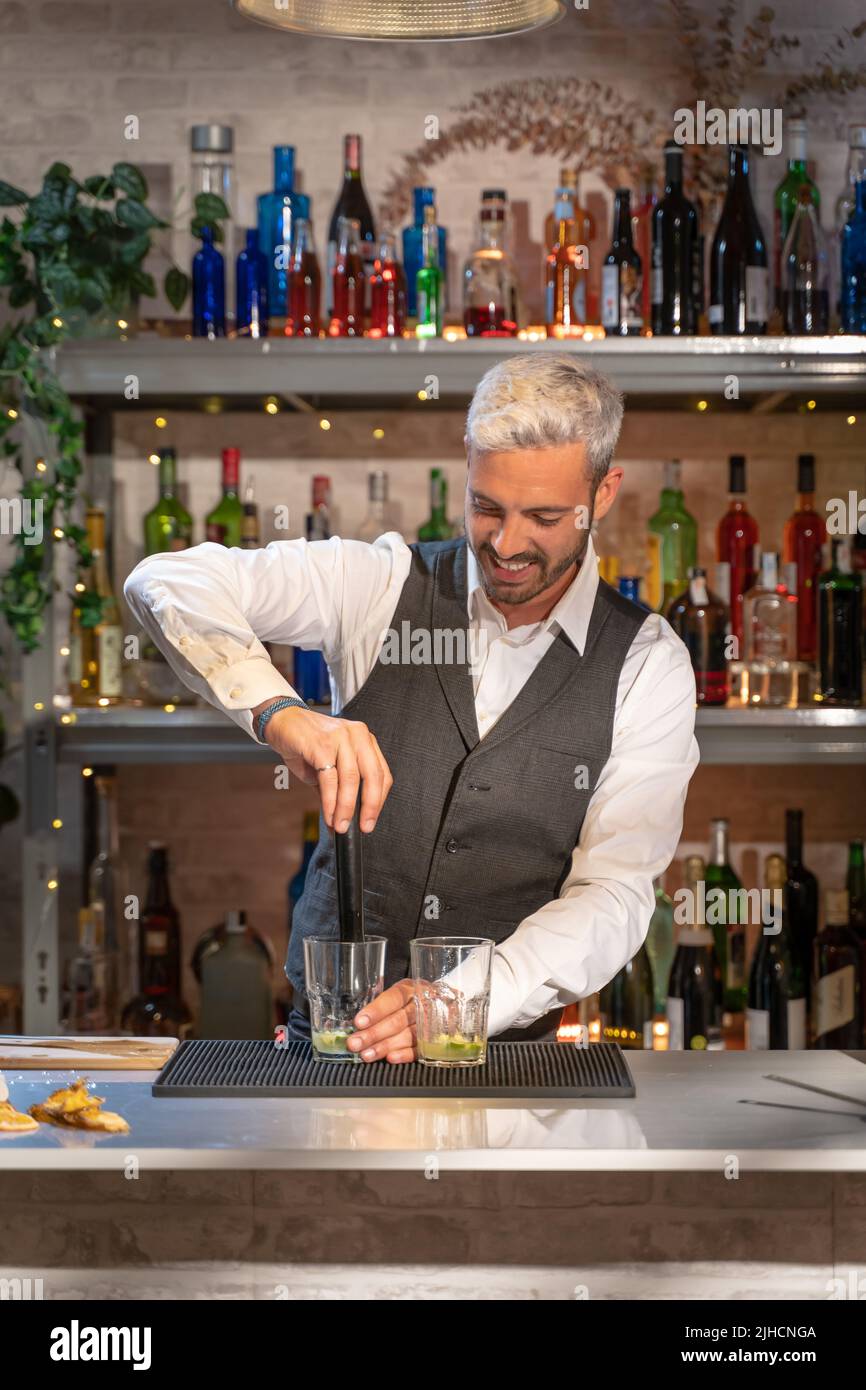 Elegant barman making cocktail Mojito in night club adding ingredients ...