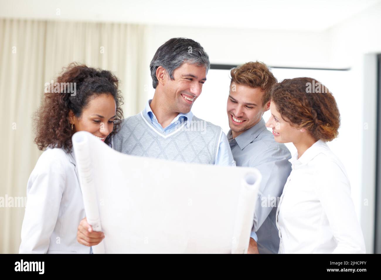 Looking over their group design. a group of four architects looking ...