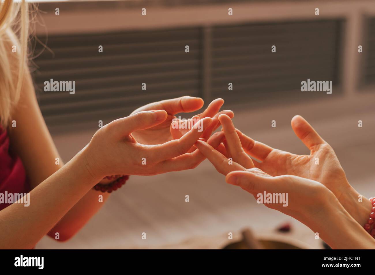 The hands of two women are intertwined into a castle, engaged in energy ...