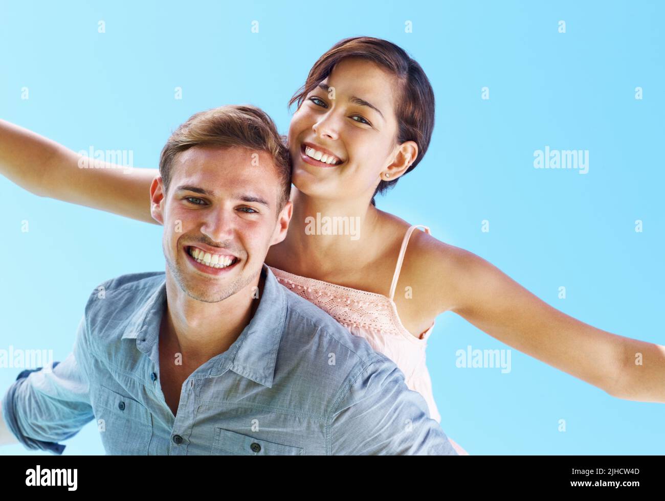 Couple enjoying piggyback ride with arms outstretched. Portrait of ...