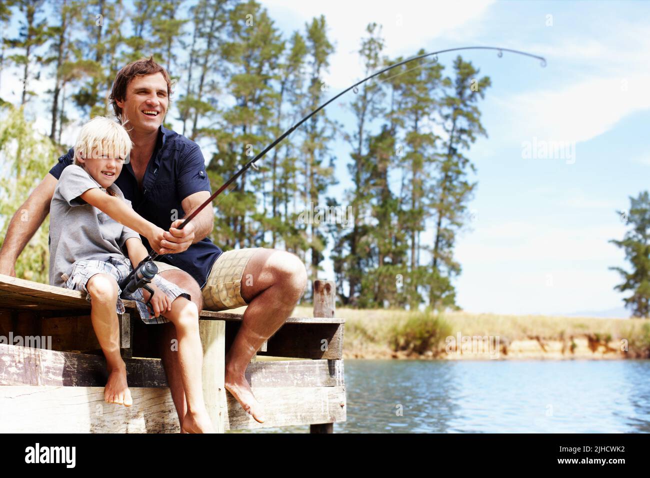 Thats it,youve hooked a big one. Excited father helping his son reel in ...