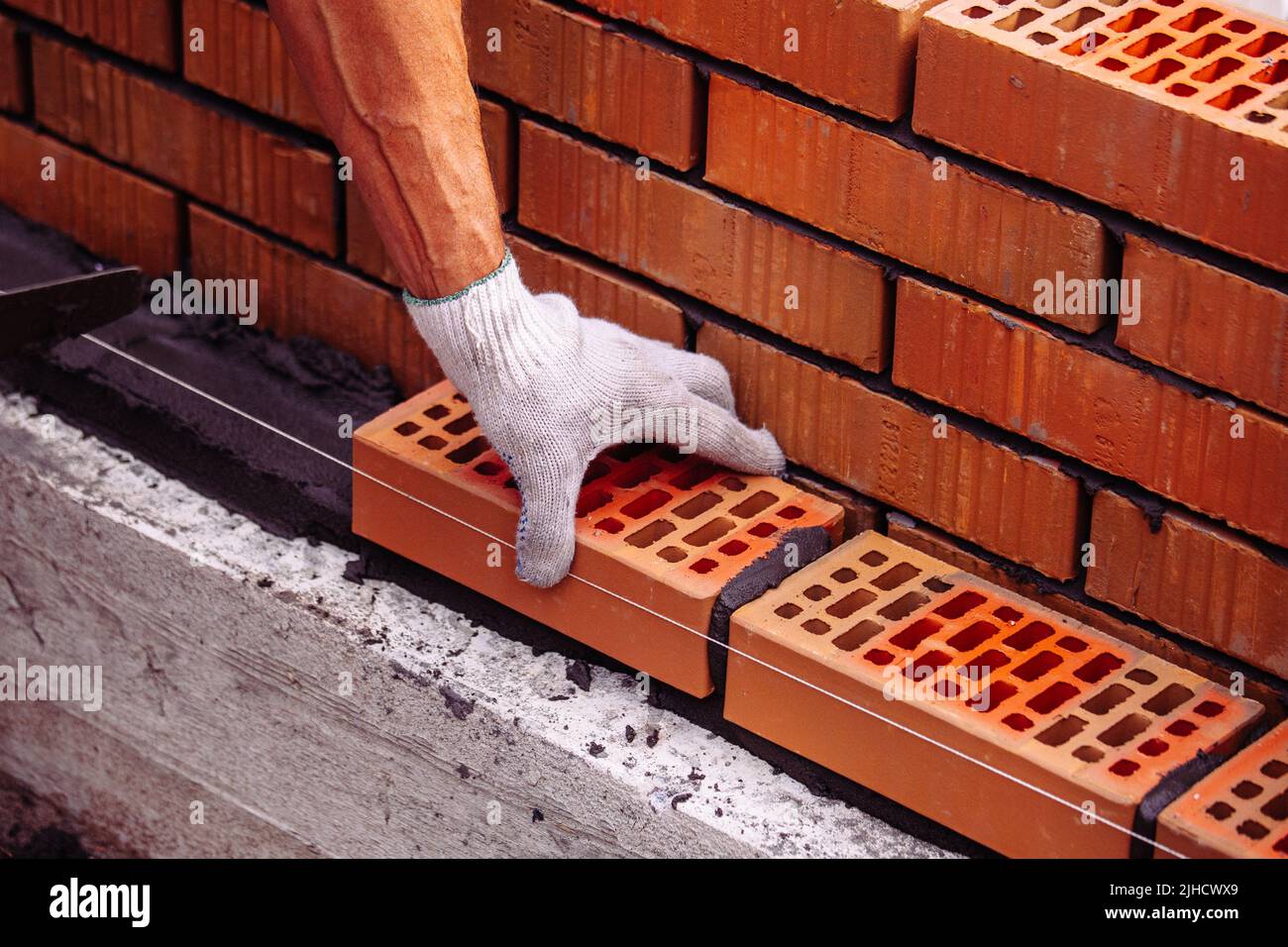 Builder laying bricks on construction site Stock Photo - Alamy
