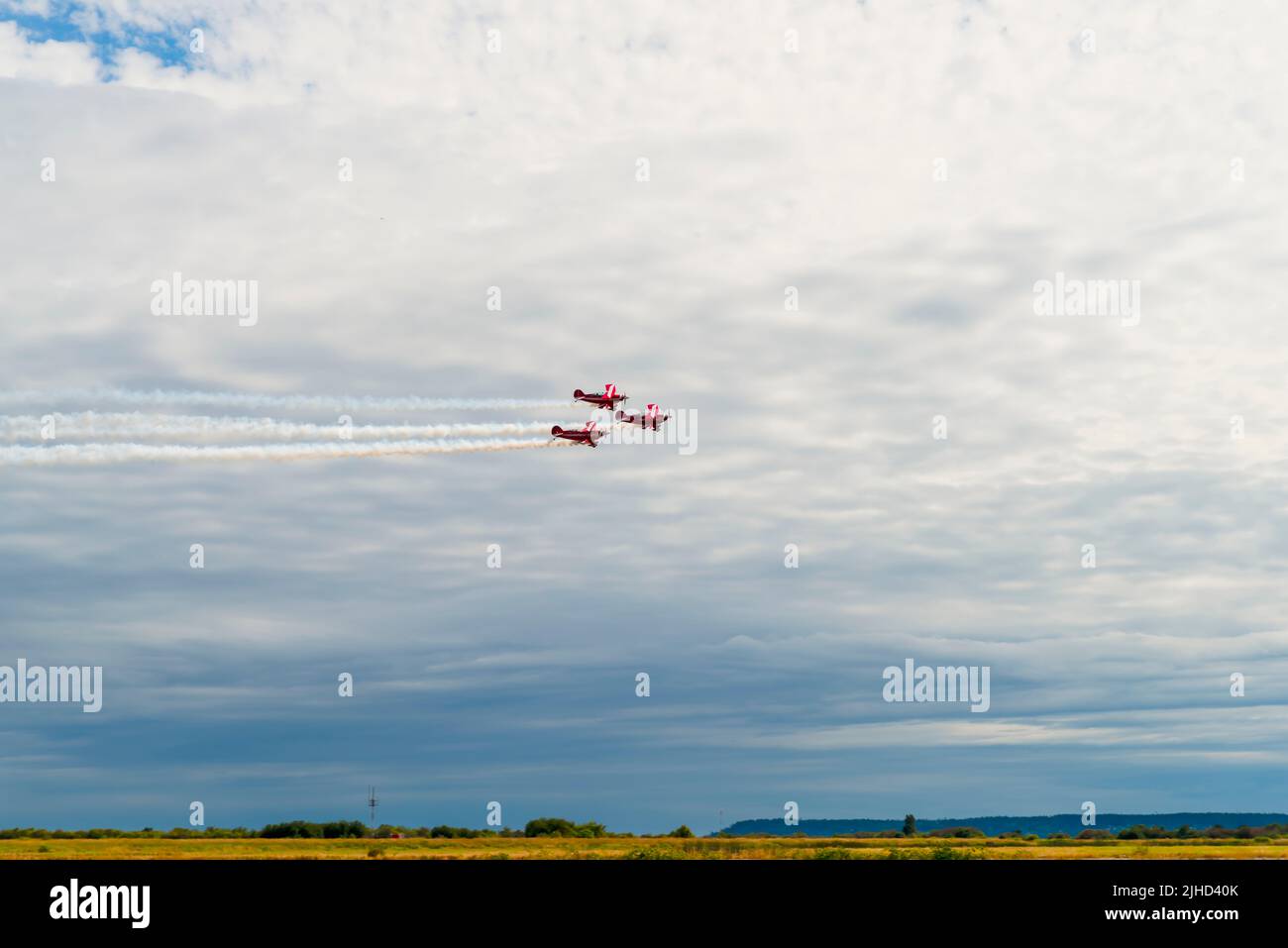 three red planes are flying in a cloudy sky over a yellow field Stock ...